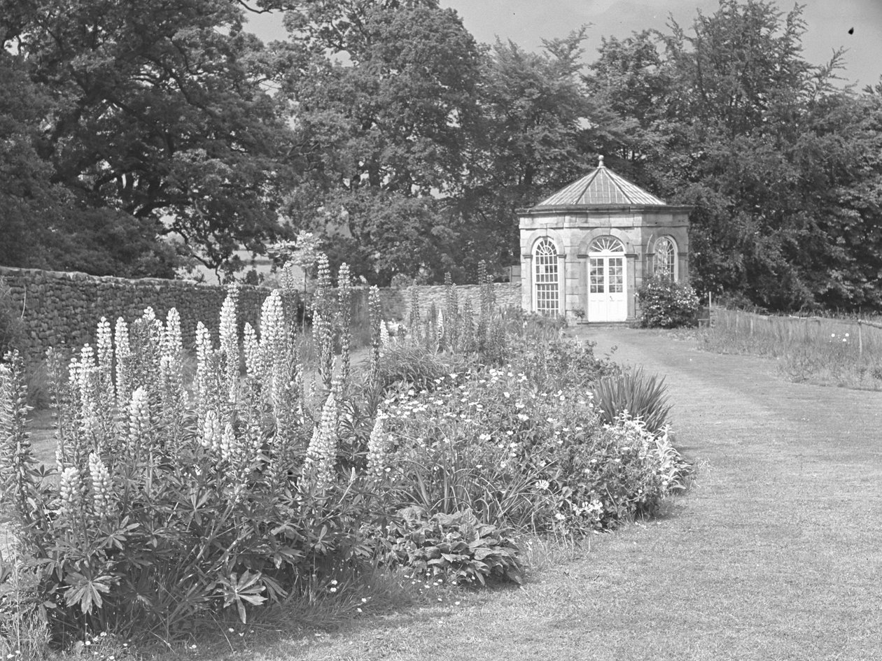Altana lub domek w ogrodzie z trawnikiem i rabatami kwiatowymi